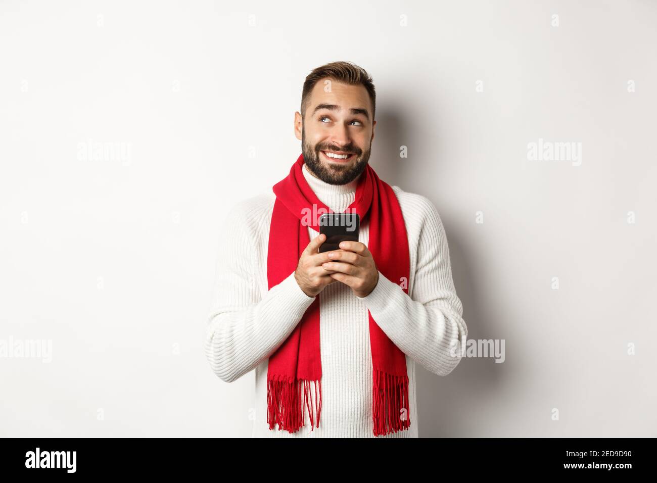 Man thinking while texting message on mobile phone, smiling and ...