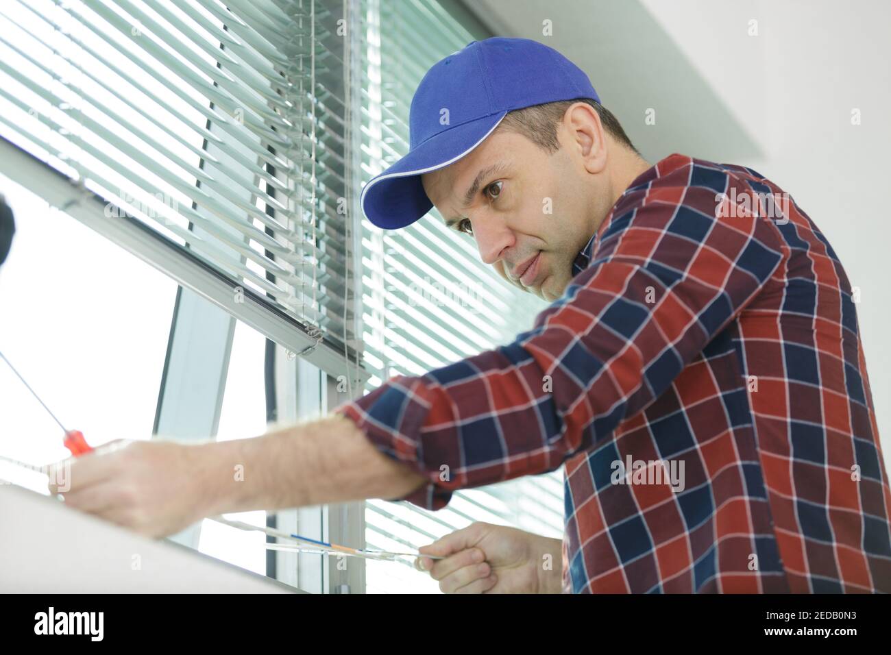 a workman fixing window blind Stock Photo - Alamy