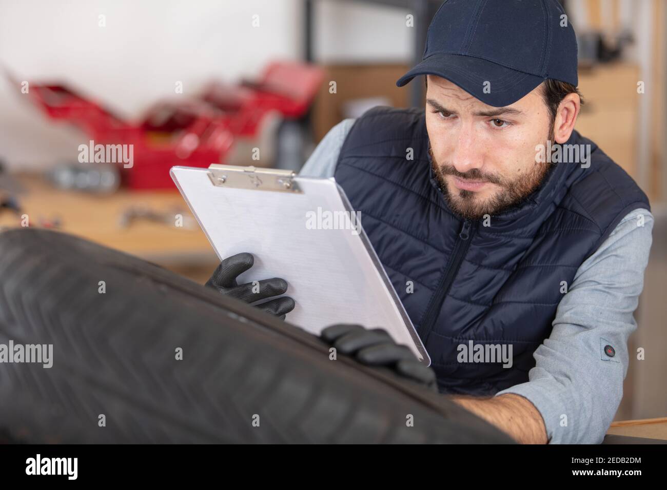 man with clipboard checking tyre Stock Photo - Alamy