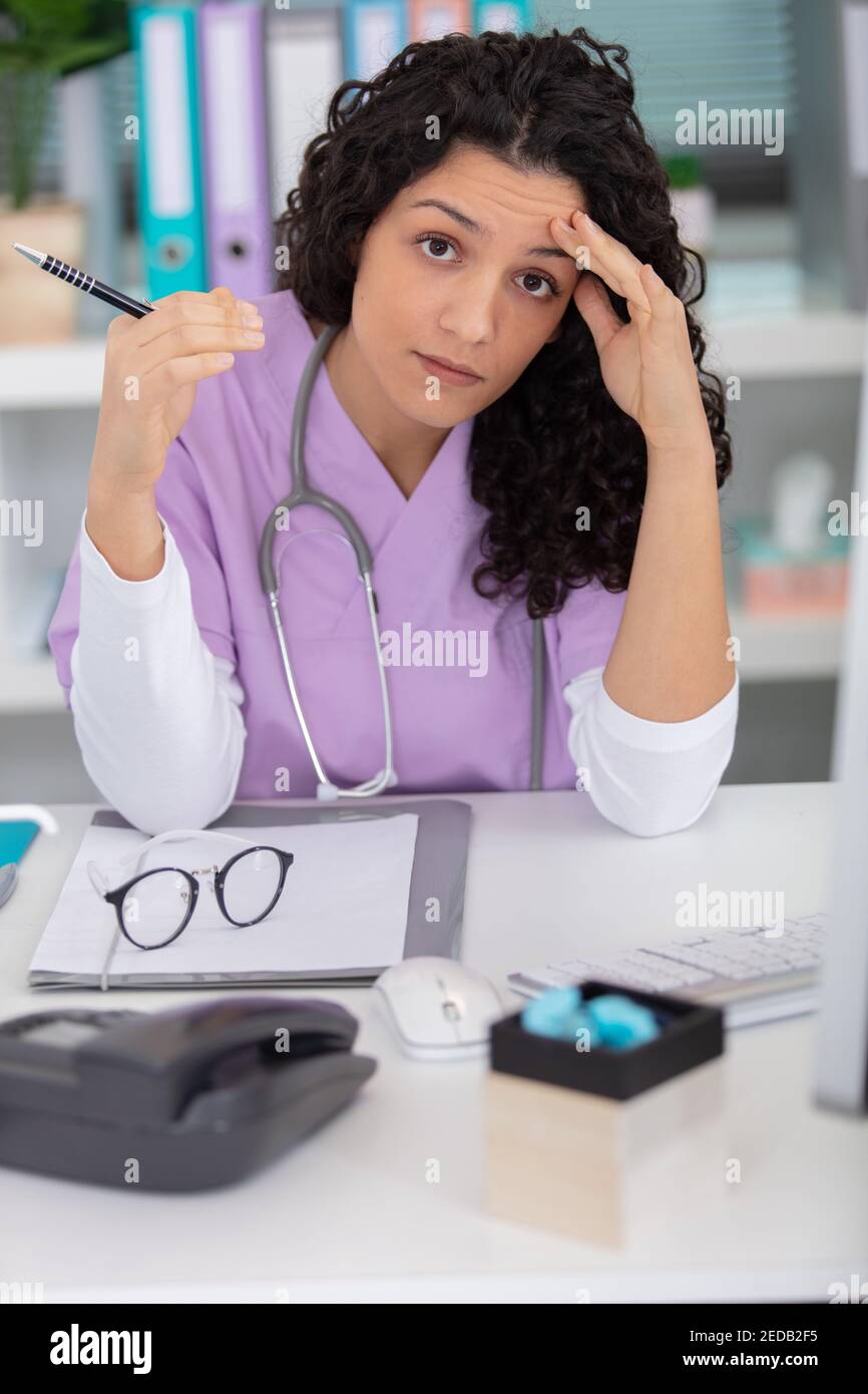 stressed nurse at her desk doing paperwork Stock Photo - Alamy
