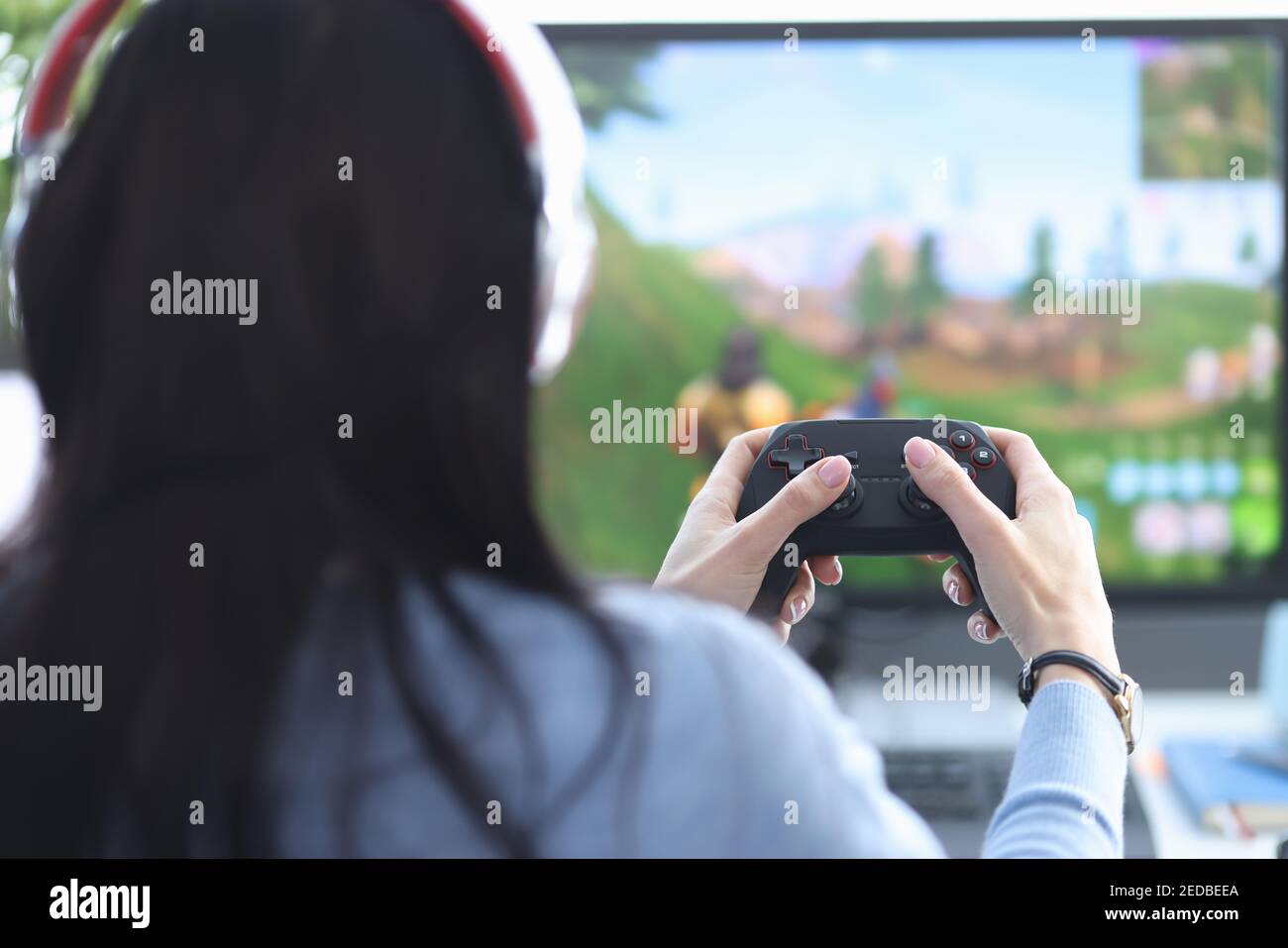 Female gamer sits with her back holding game joystick and plays game on ...