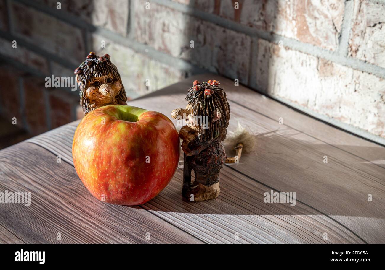 Big red apple and funny trolls figures on the wooden table against the ...