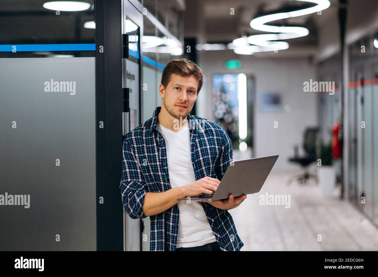 Successful freelancer stand in modern office, using laptop. Attractive ...