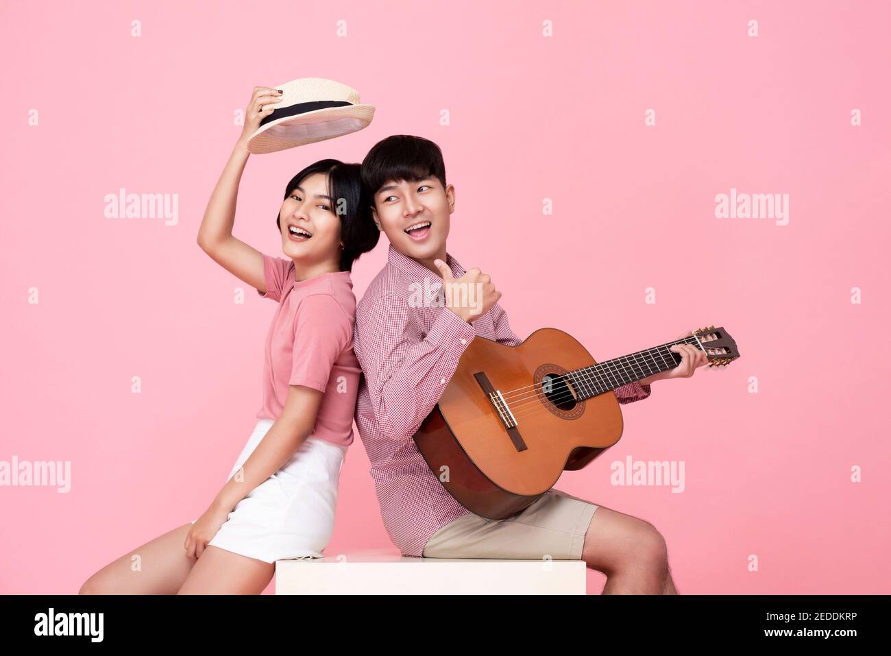 Happy young Asian man playing guitar and singing with his girlfriend ...