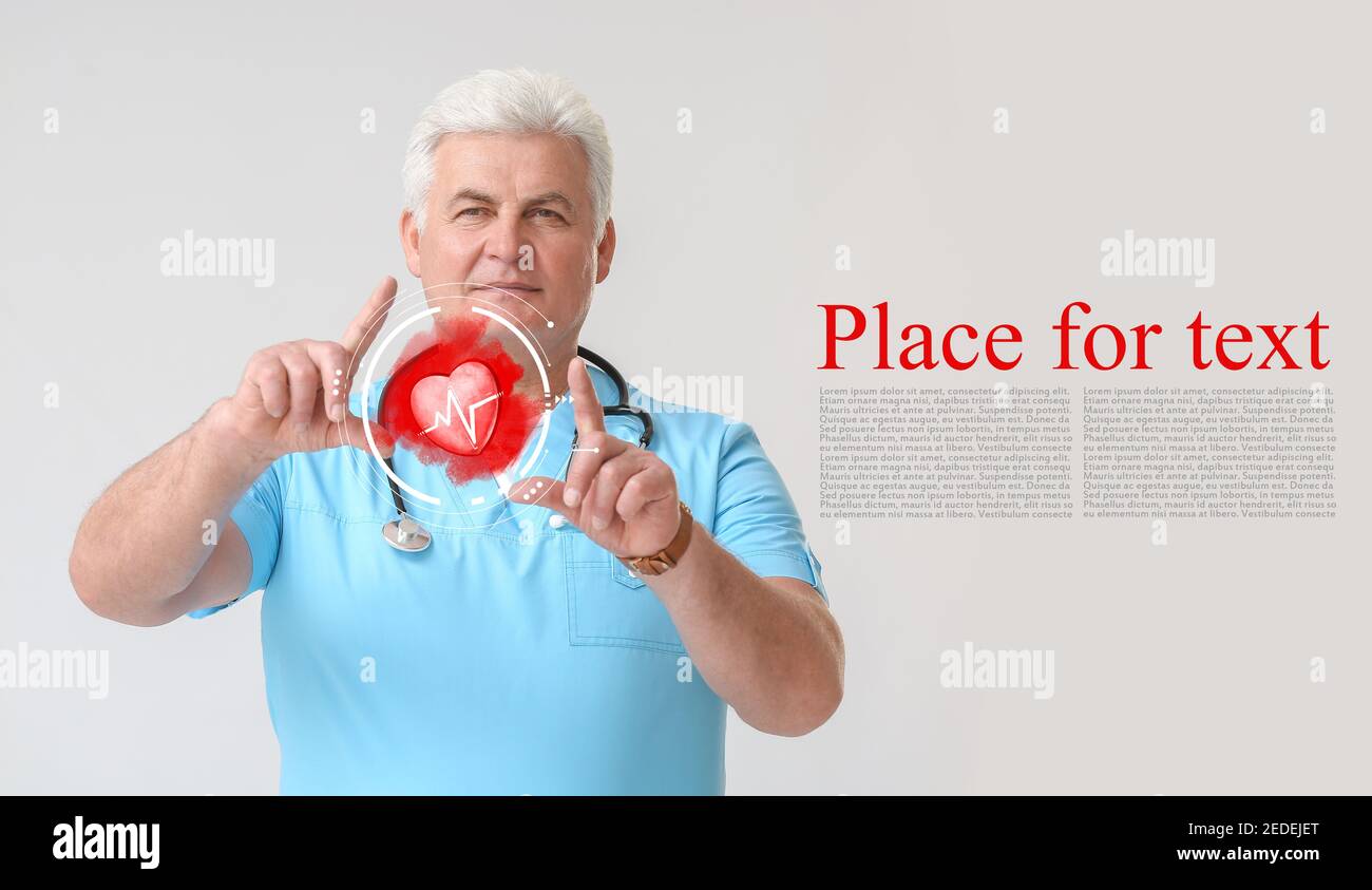 Mature cardiologist using virtual screen on grey background with space ...