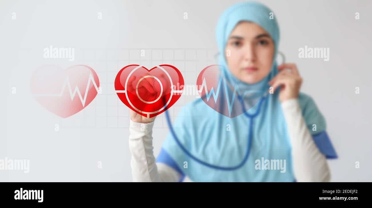 Female Muslim cardiologist with stethoscope using virtual screen on ...