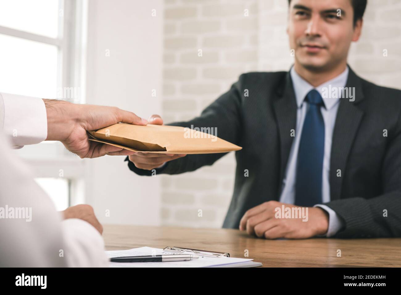 Young attractive businessman receiving money inside a brown envelope ...