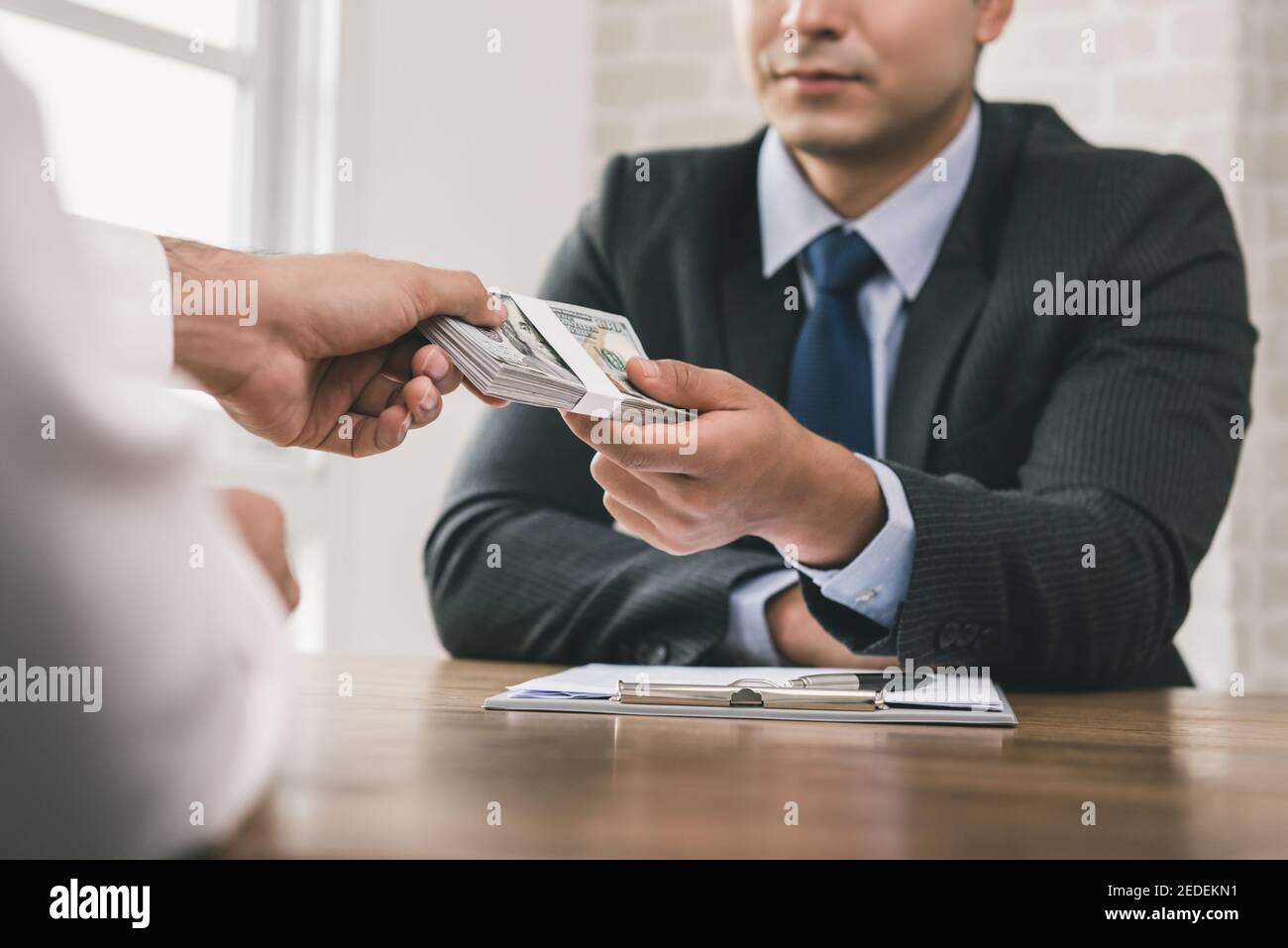 Man handing over cash to a young businessman partner after signing the ...