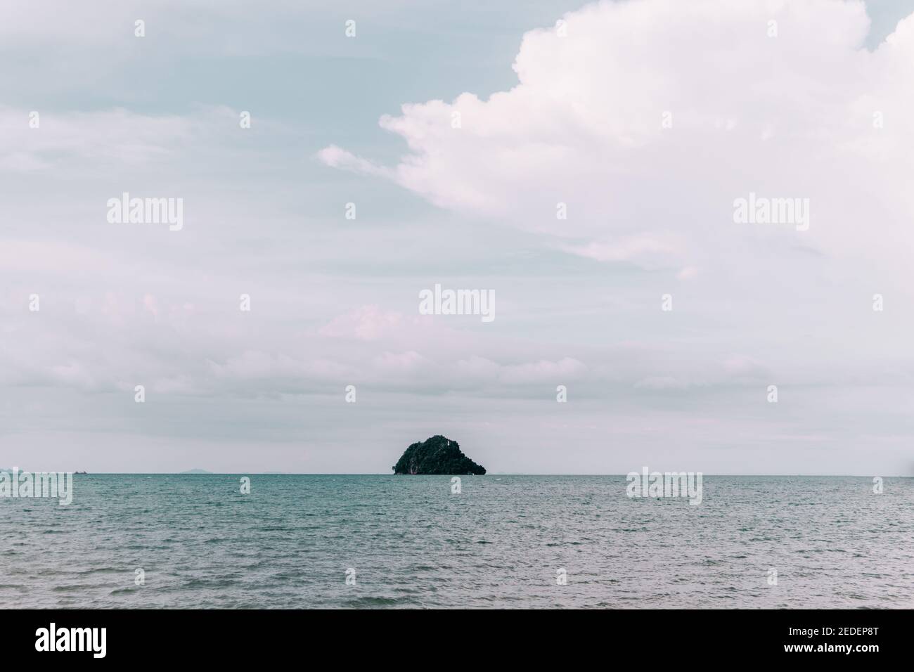 Beautiful view of the wavy ocean with a small island gleaming under the ...