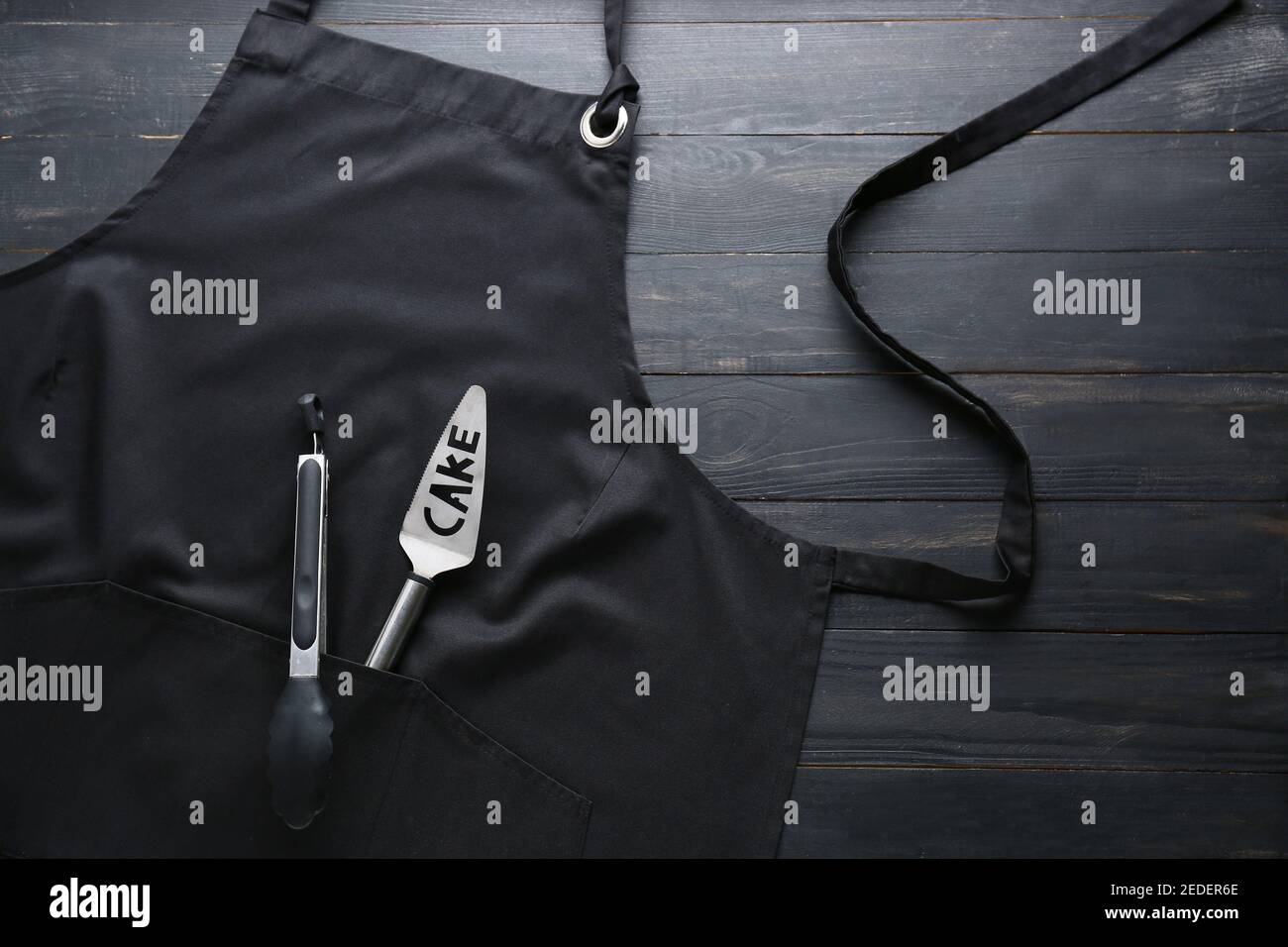 Clean apron and kitchen utensils on dark background Stock Photo - Alamy