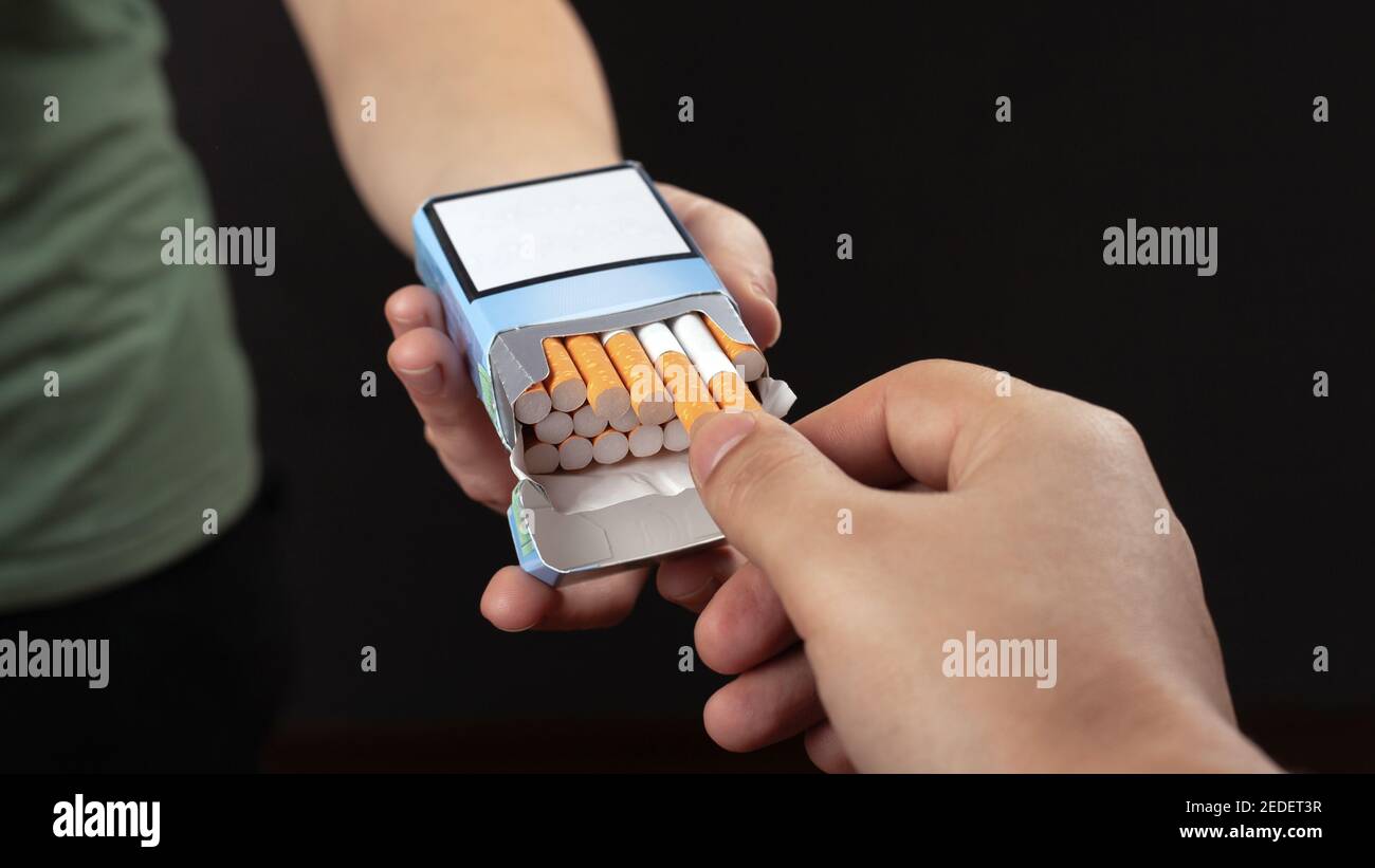 give a cigarette from a pack,nicotine addiction closeup Stock Photo - Alamy