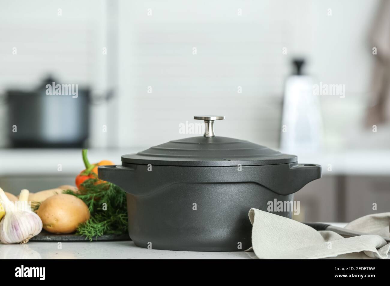 Cooking pot and vegetables on table in kitchen Stock Photo - Alamy