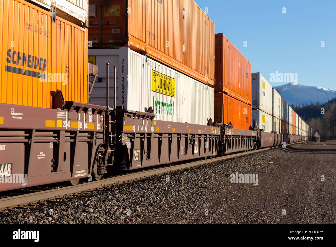 A line of shipping container well cars rolling through the BNSF rail yard in Troy, Montana ...