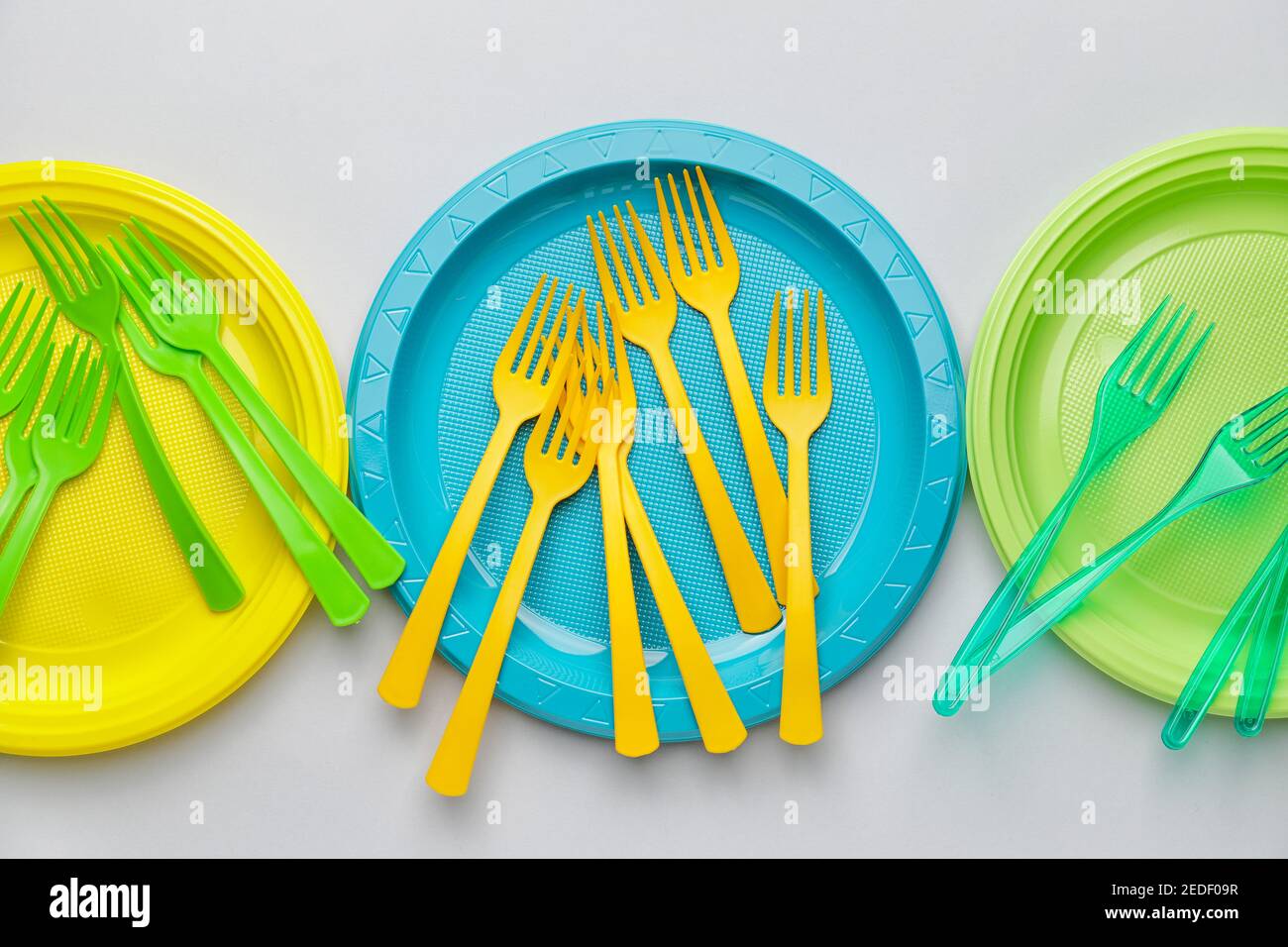 Plastic forks and plates on light background Stock Photo - Alamy