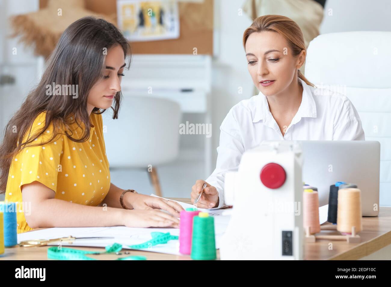 Female fashion designer and assistant working in studio Stock Photo - Alamy