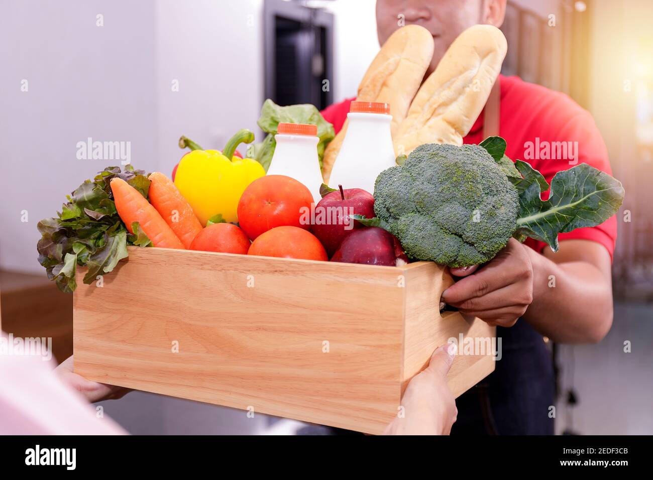 Asian deliver man in red uniform handling wooden crate box of food ...