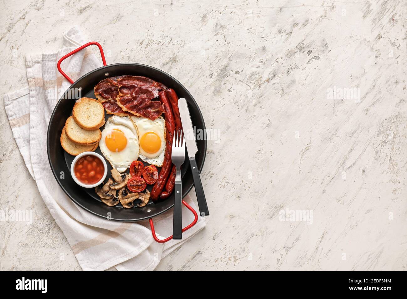 Traditional English breakfast with fried eggs in pan on light ...