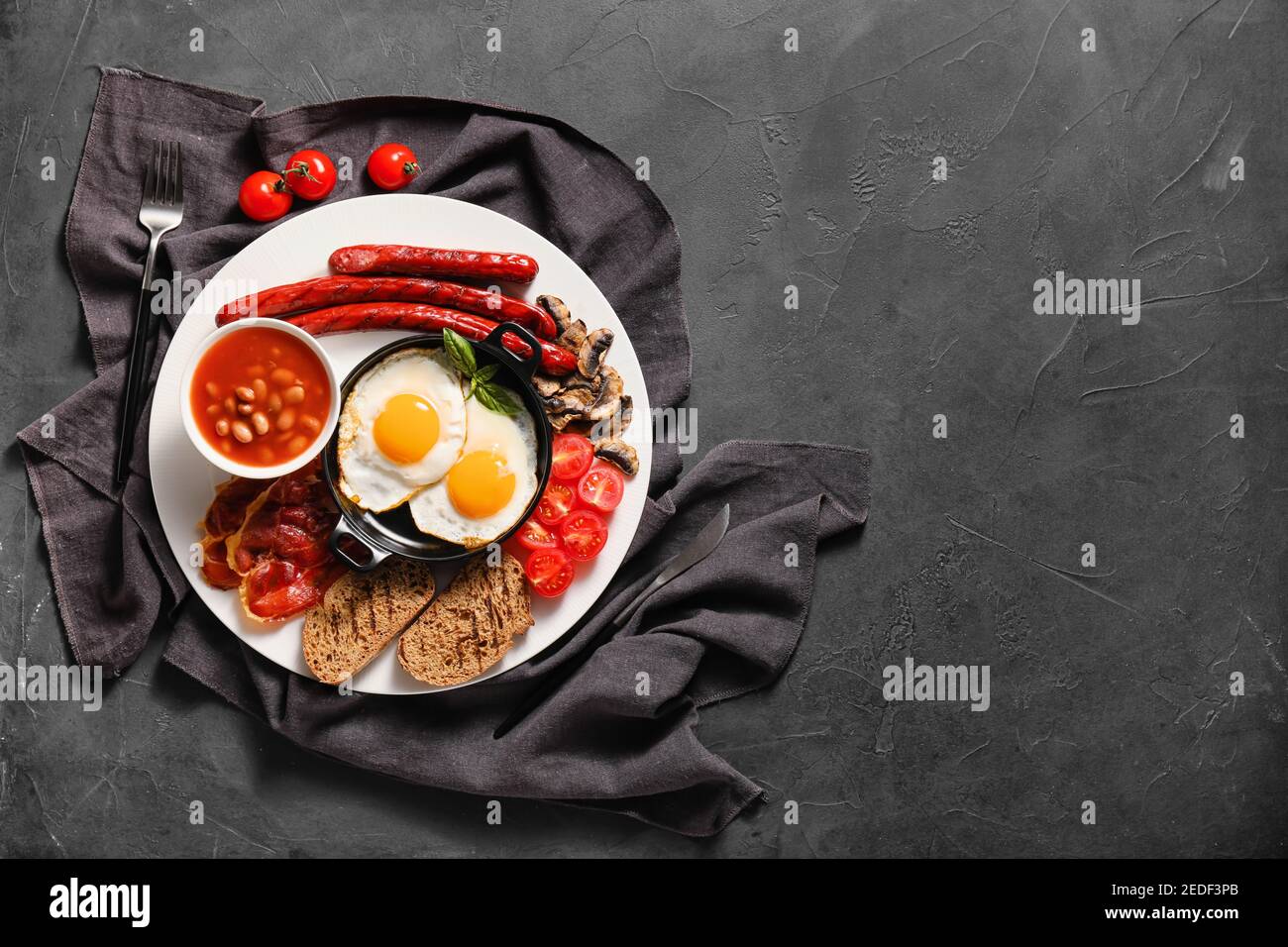 Traditional English breakfast with fried eggs in plate on dark ...