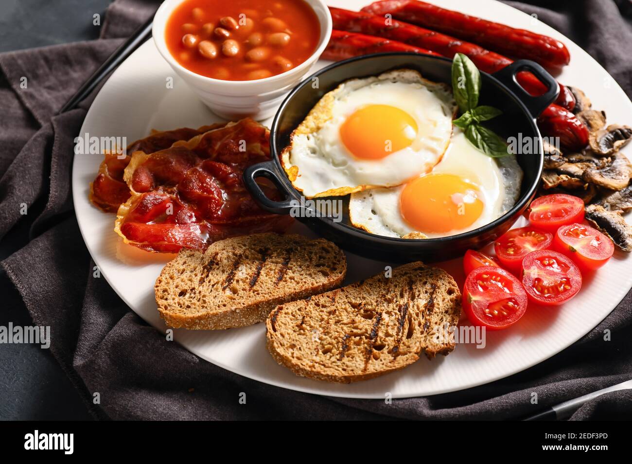 Traditional English breakfast with fried eggs in plate on dark ...