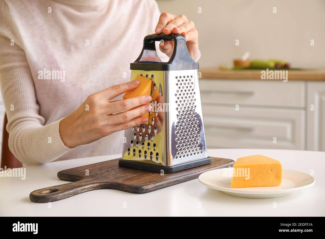 Woman grating cheese on kitchen table Stock Photo - Alamy