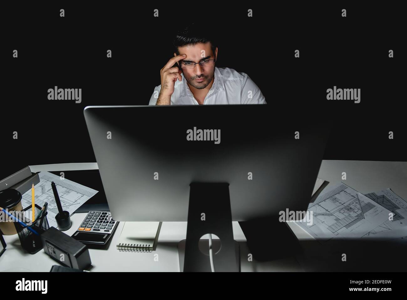 Serious Asian businessman or architect working late at night in the ...