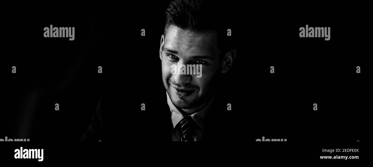 Sly man in formal business suit staring at interlocutor in dark shadow ...