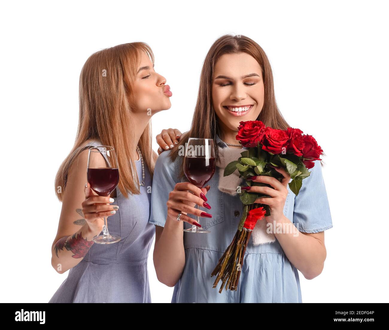 Young transgender couple with glasses of wine and flowers on white ...
