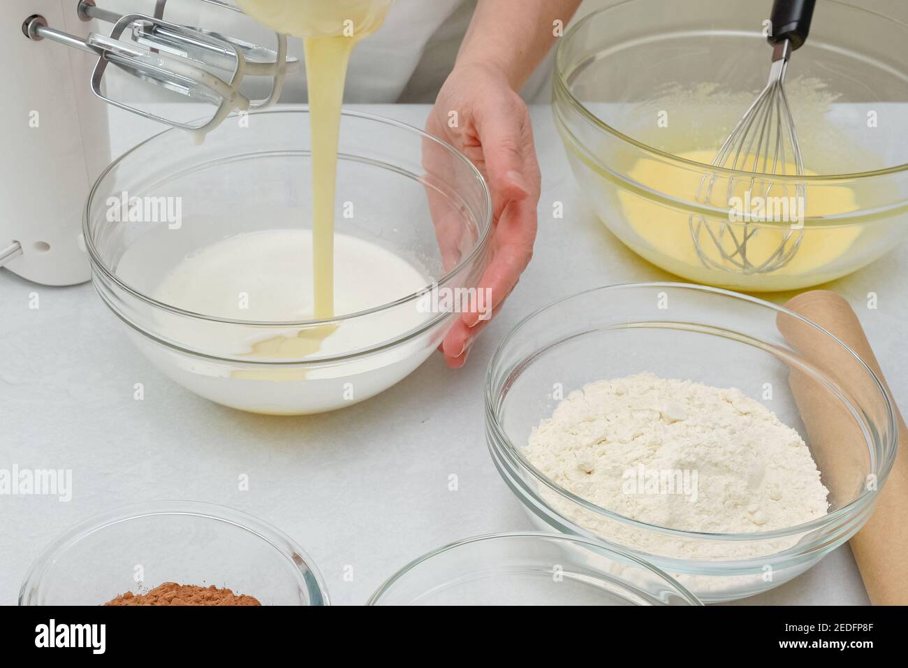 Close up baking process. Chef adds condensed milk into a bowl with ...