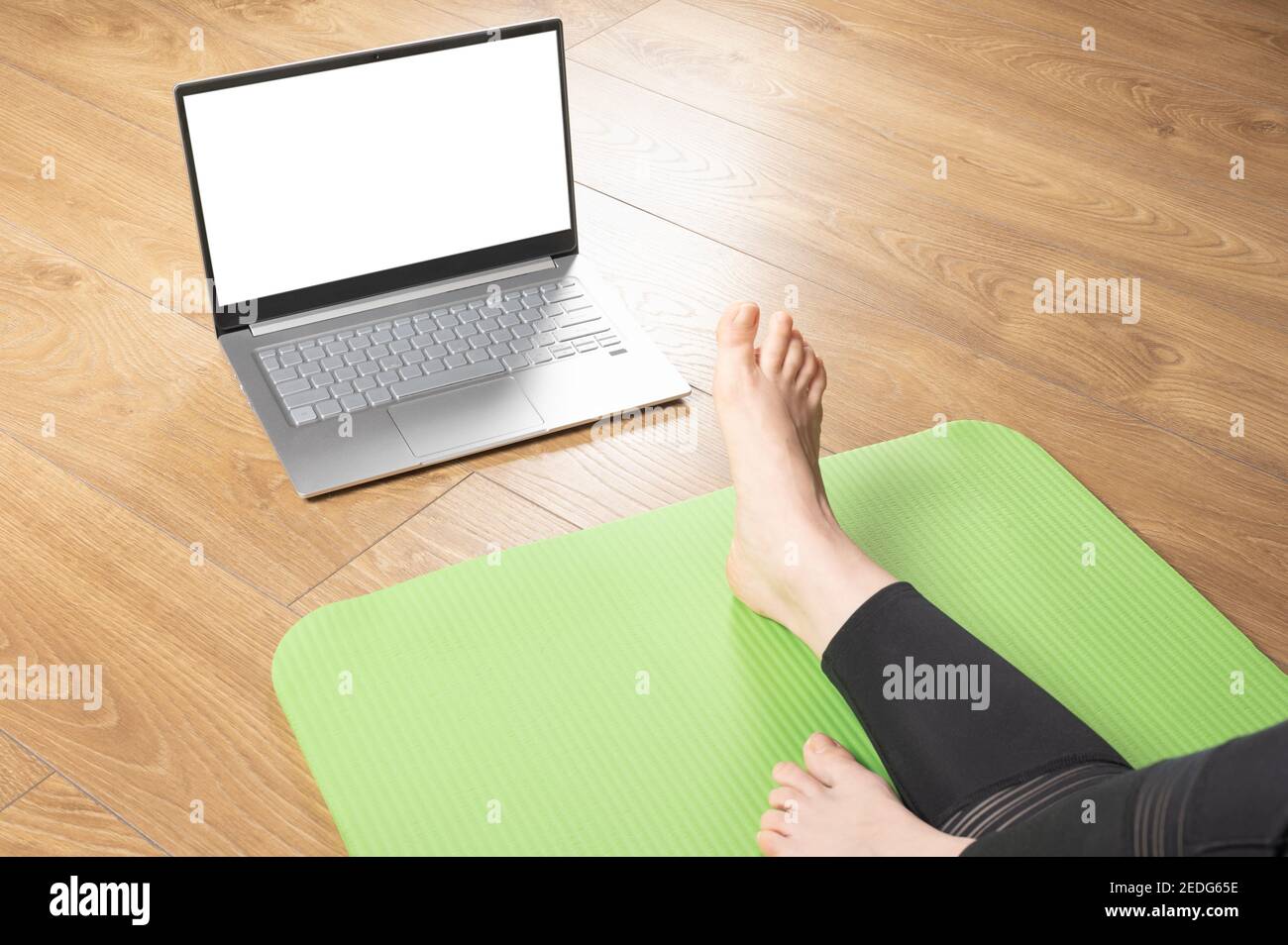 woman sits on yoga mat with her legs stretched out and looks into ...