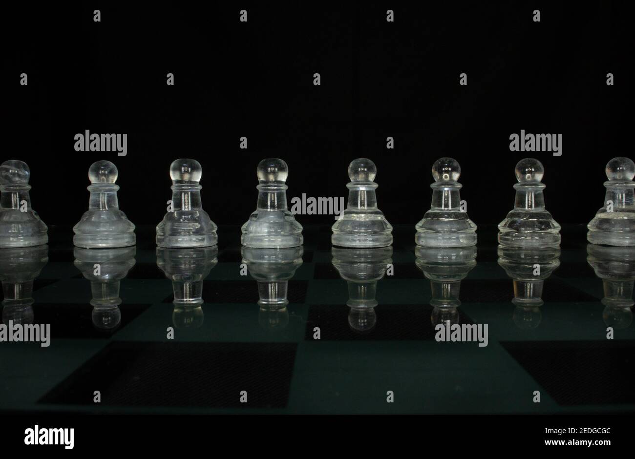 full set of eight clear chess piece pawns isolated on a chequered chess ...