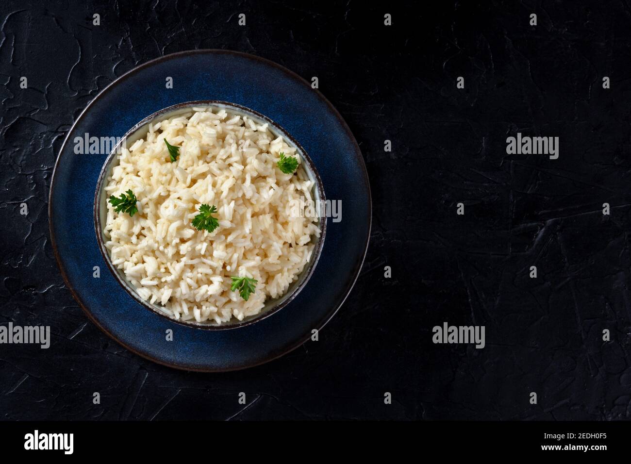 White rice, cooked, shot from above on a dark background with a place ...