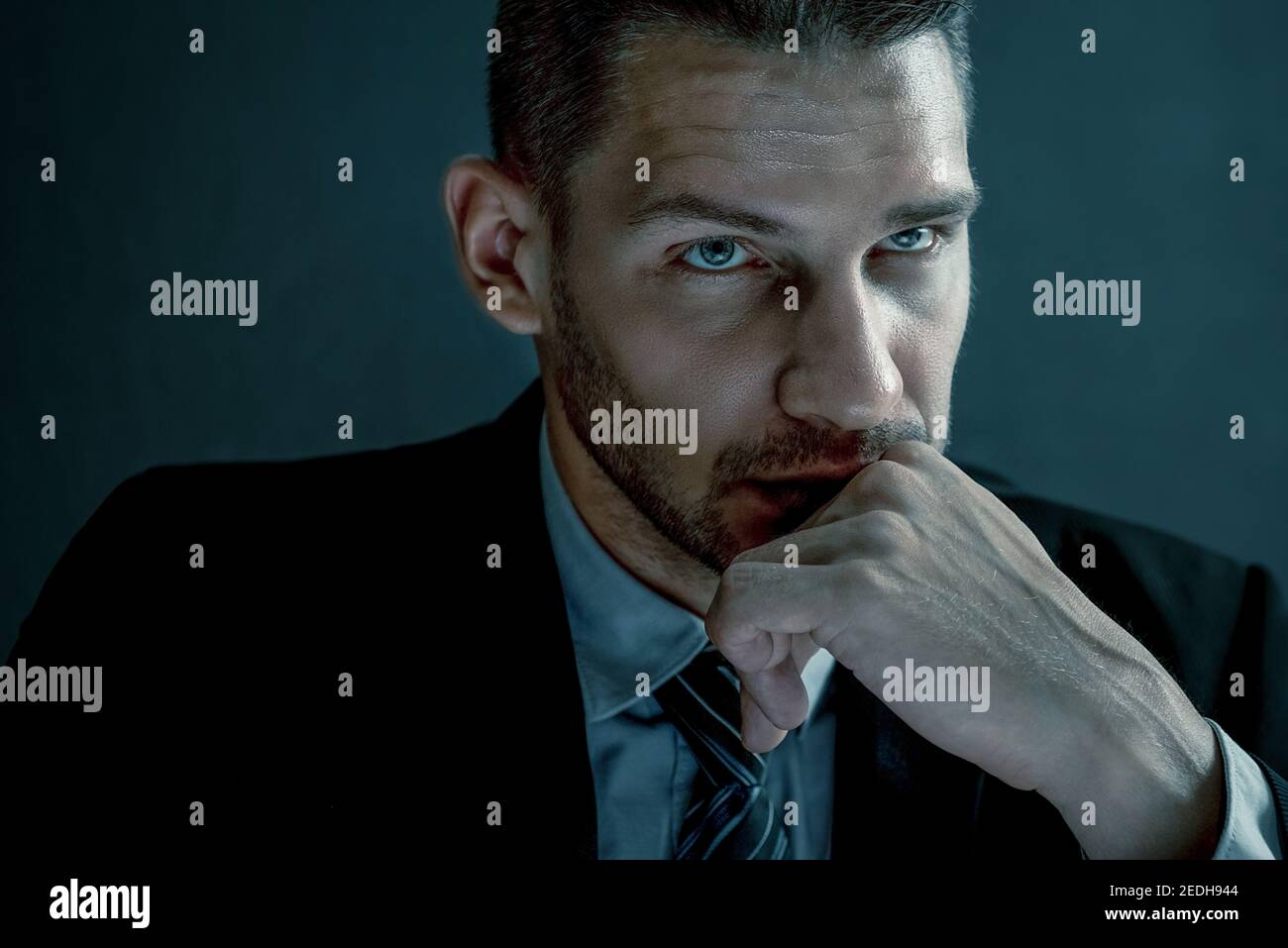 Pensive man interviewer in shadow with serious face staring at ...