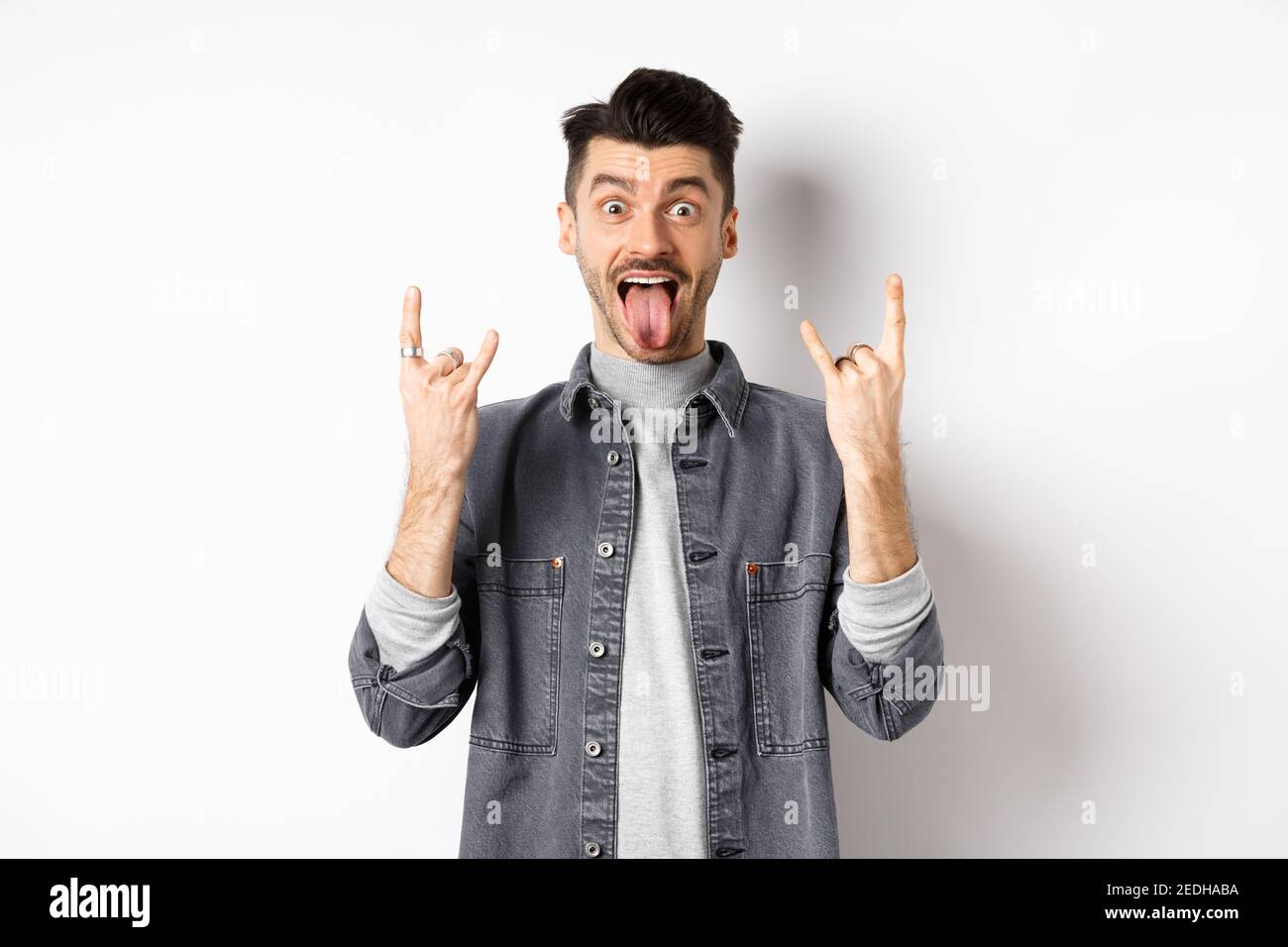 Excited funny guy showing tongue and heavy metal horns sign, enjoying ...