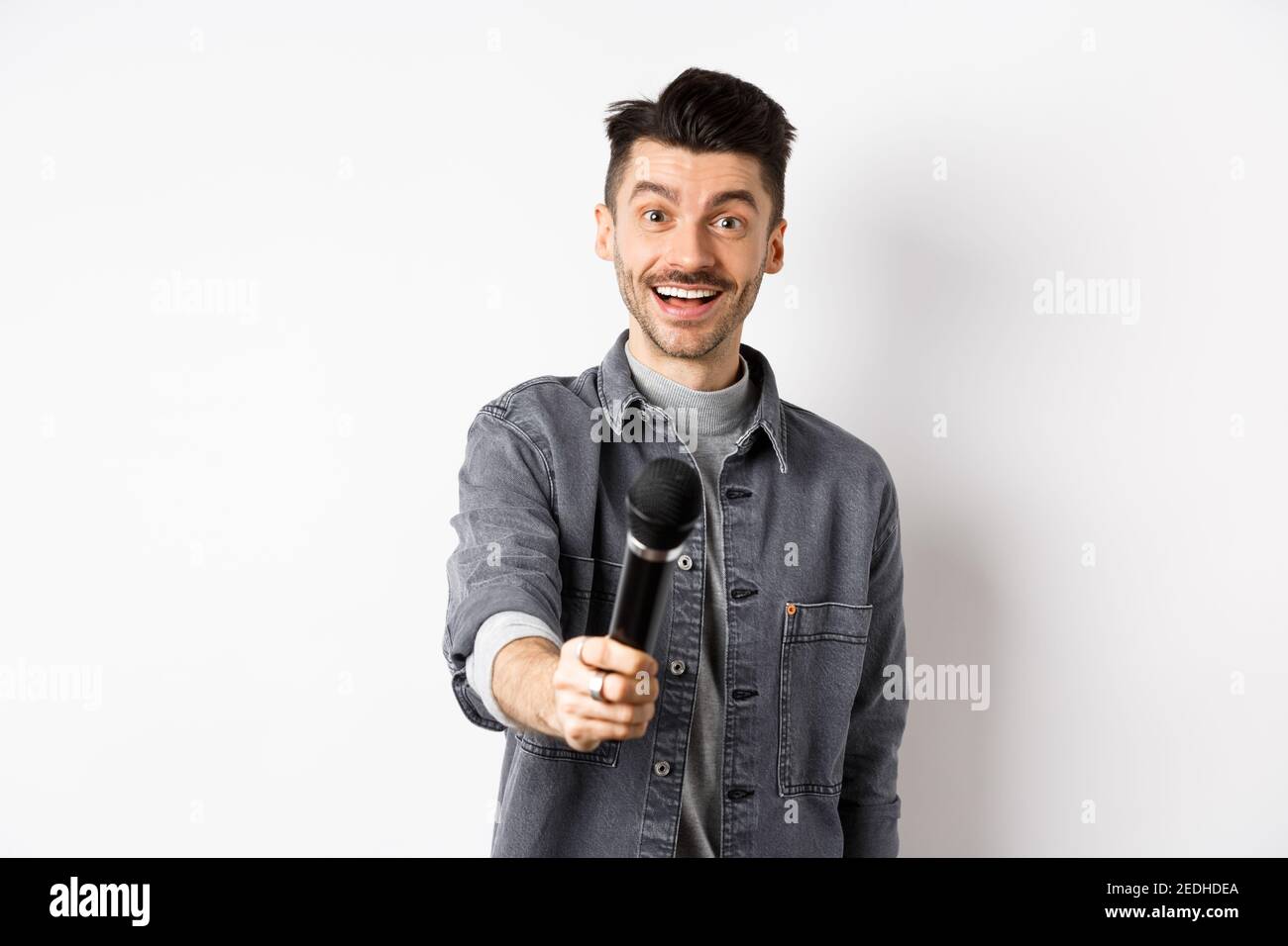 Handsome smiling man stretch out hand with microphone, giving you mic ...