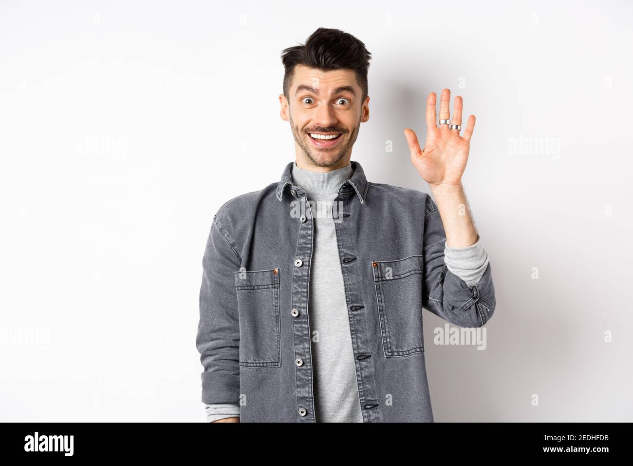 Friendly stylish man saying hello and waiving hand, smiling cheerful ...