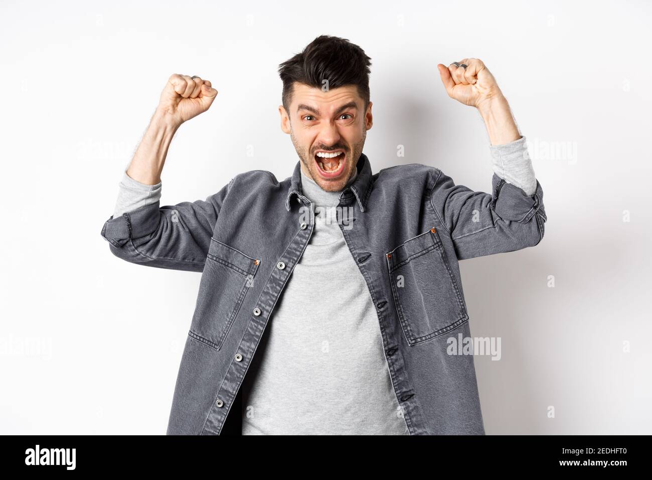 Motivated young man shouting and raising hands up, watching sports game ...
