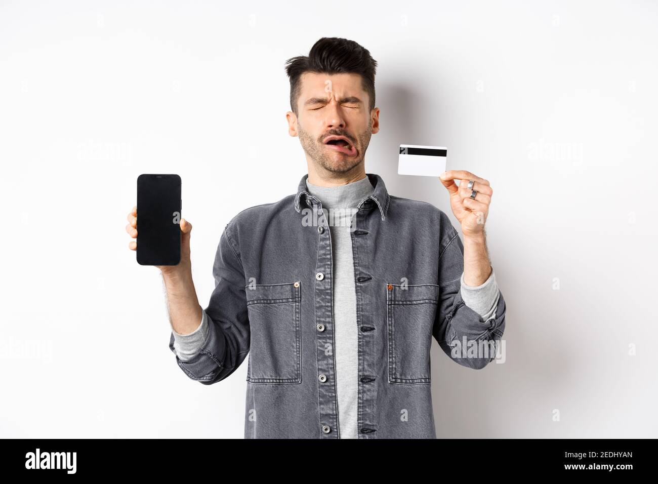 Sad crying man show empty mobile phone screen and plastic credit card ...