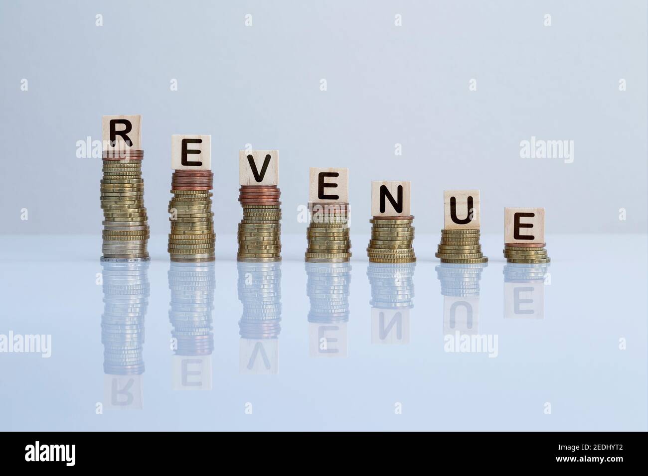 Word "REVENUE" on wooden blocks on top of descending stacks of coins ...