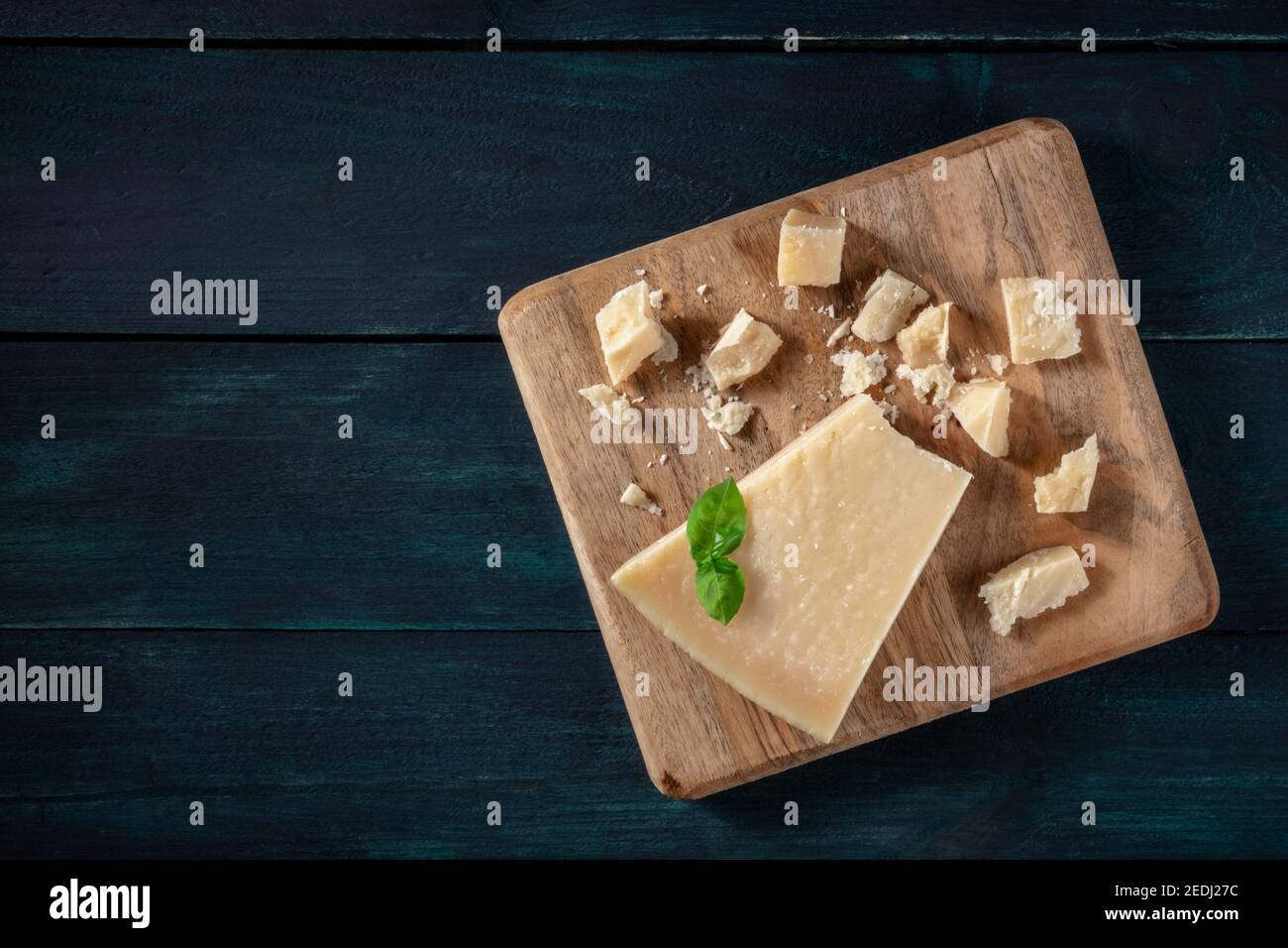 Crumbled Parmesan cheese, shot from above on a dark blue wooden ...