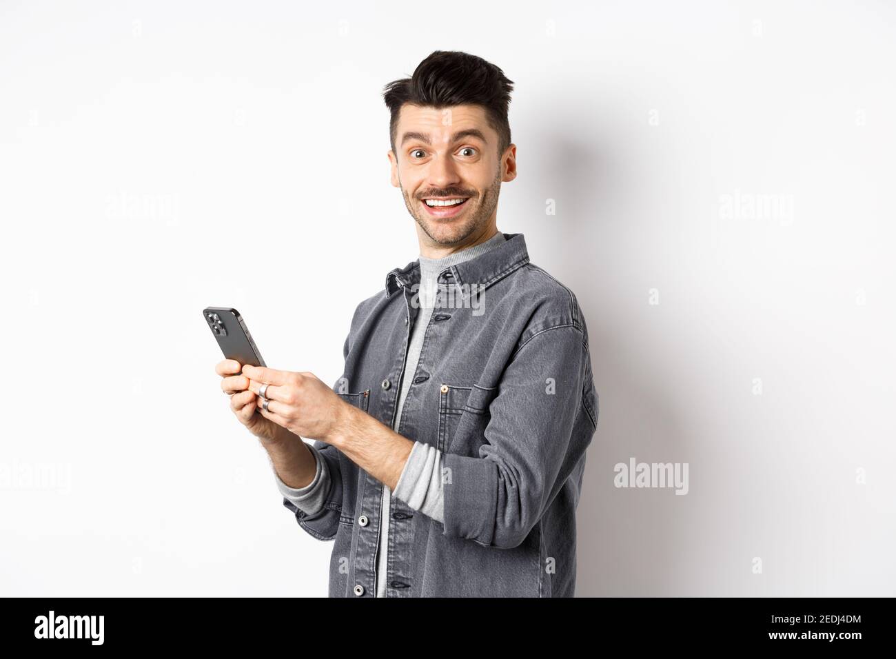 Handsome young man using smartphone and looking at camera. Caucasian ...