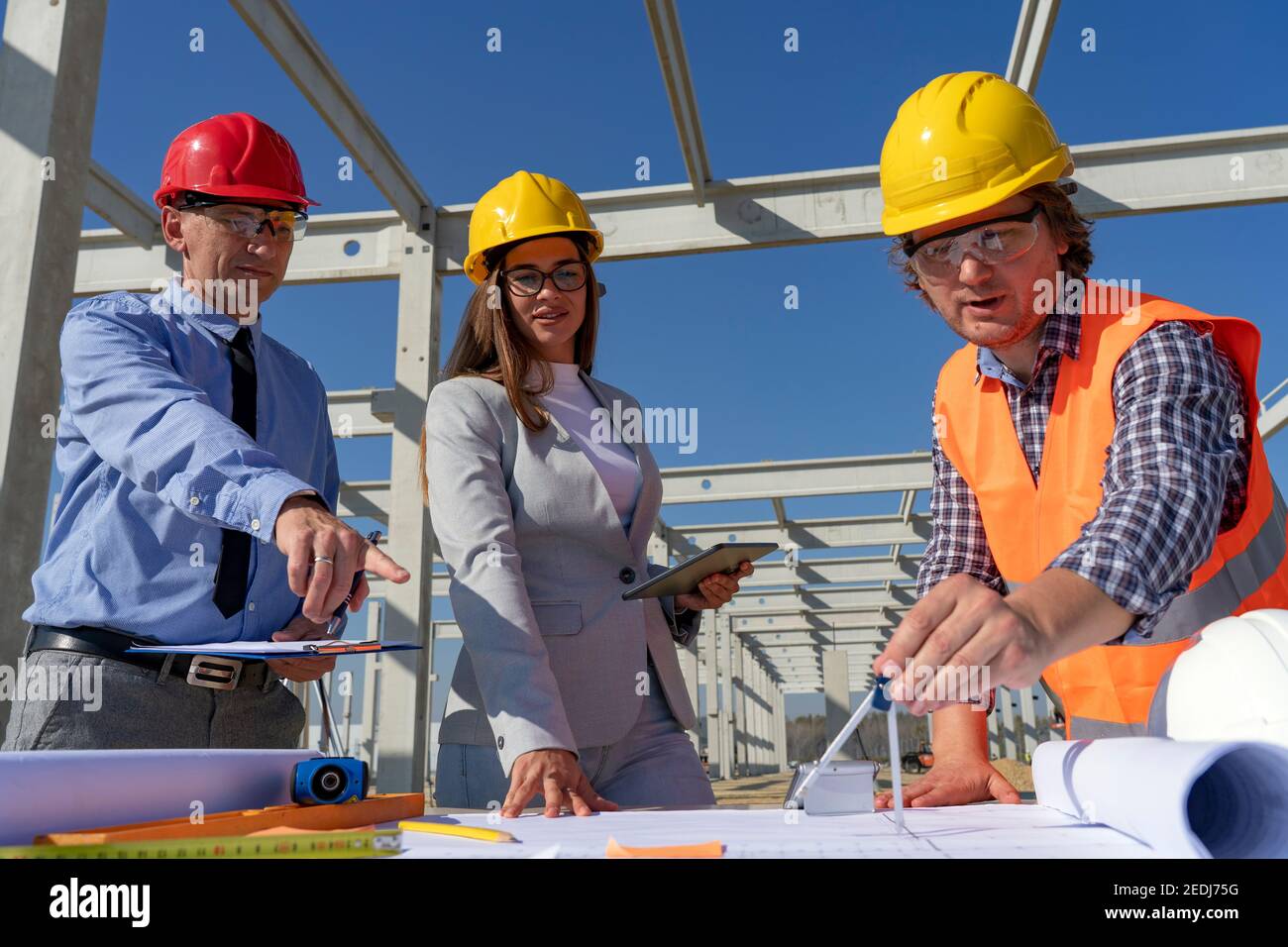 Mixed Construction Business Team in Yellow and Red Hardhats Discuss on ...