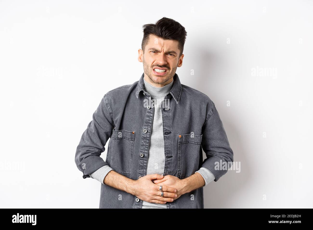 Man with stomach ache frowning and touching belly, having food poison ...