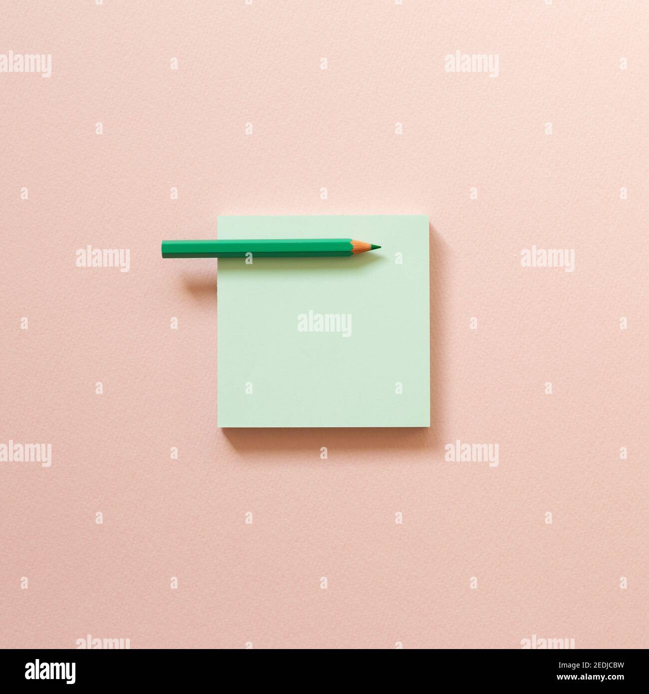 Green memo paper, sticky notes with colored pencil on pink background ...