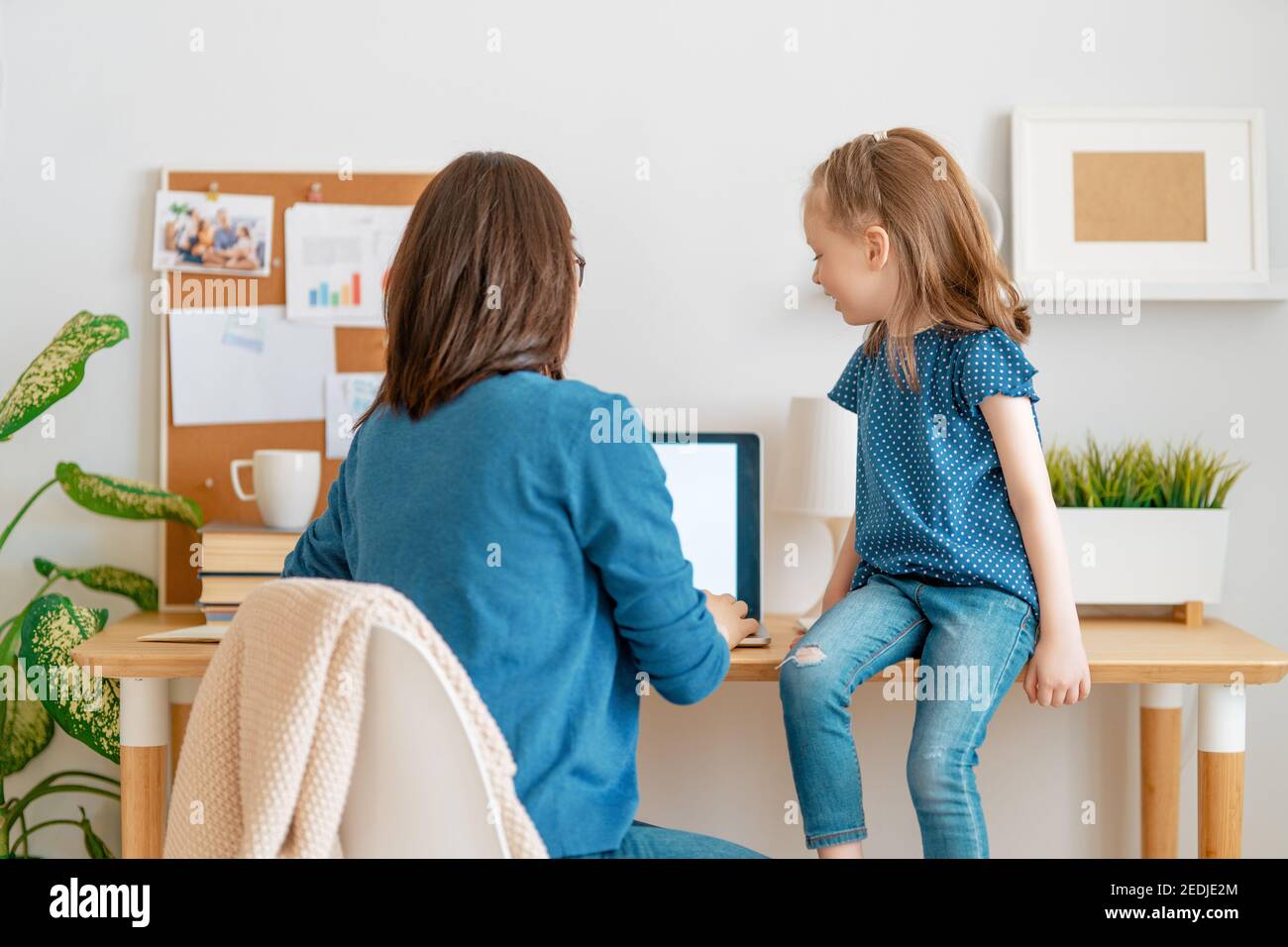 Young mother with child working on the computer. Family at home. Remote ...