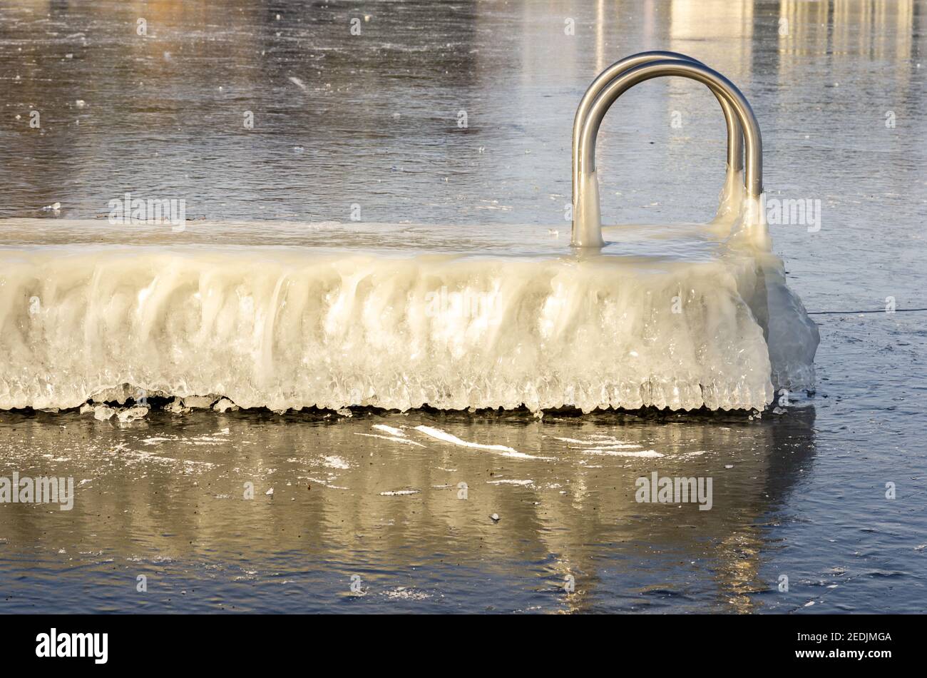 frozen bathing jetty. ice and frozen snow covered dock surrounded by a ...