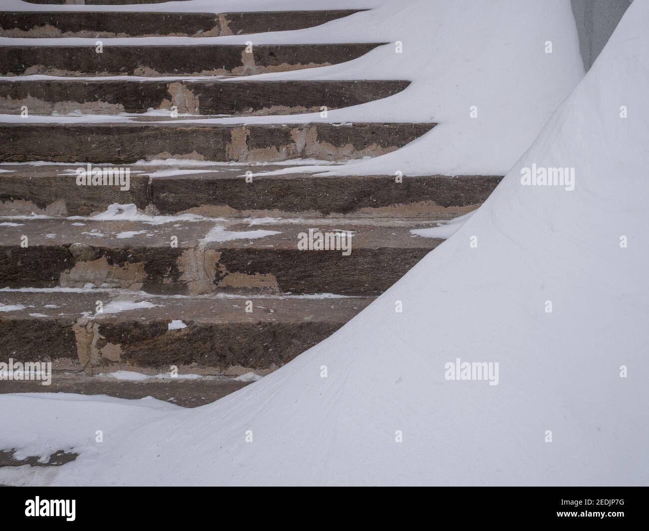 Old concrete steps of a staircase swept by snow during a snowfall on a ...