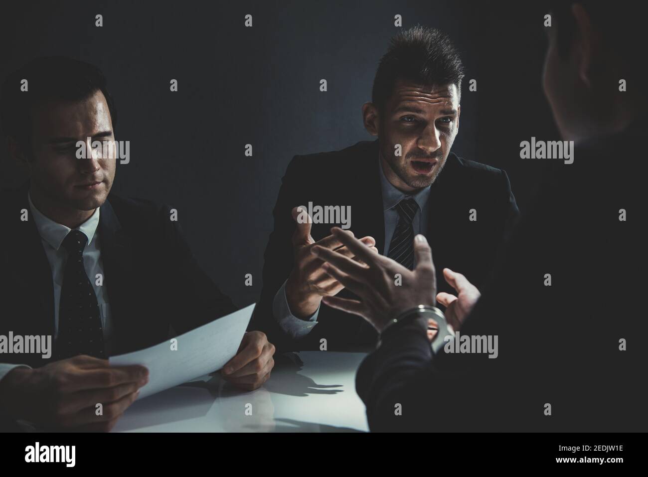 Suspect or criminal man with handcuffs being interviewed by detectives ...