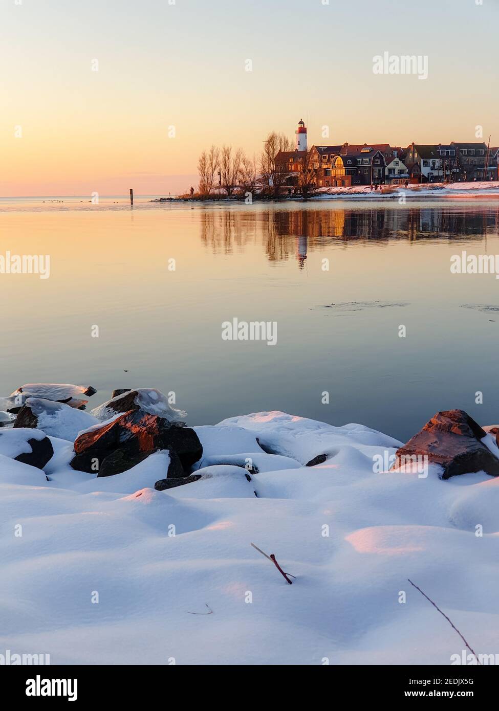 snow covered beach during wnter by Urk lighthouse in the Netherlands ...