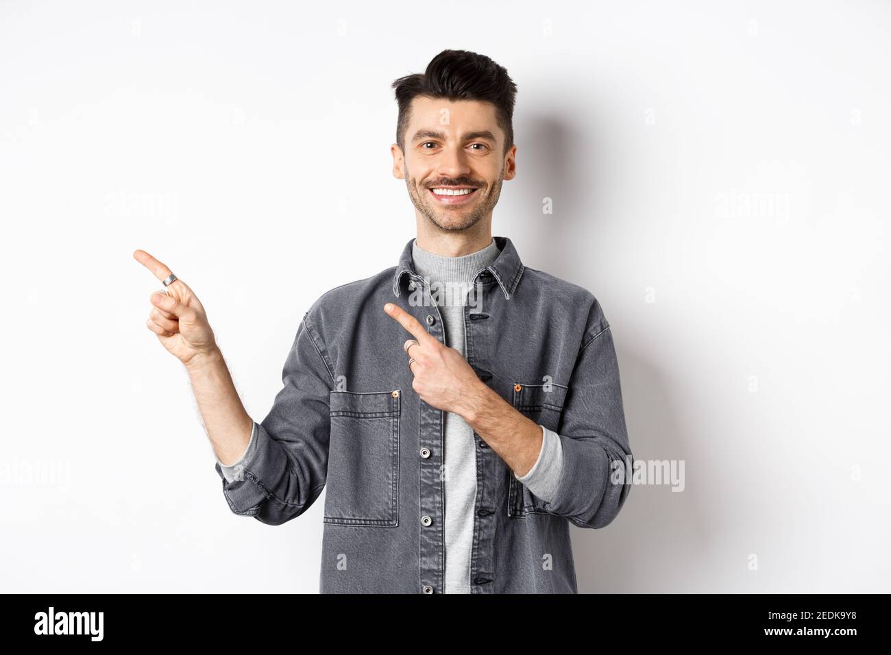 Handsome smiling man pointing fingers left, showing logo and looking ...