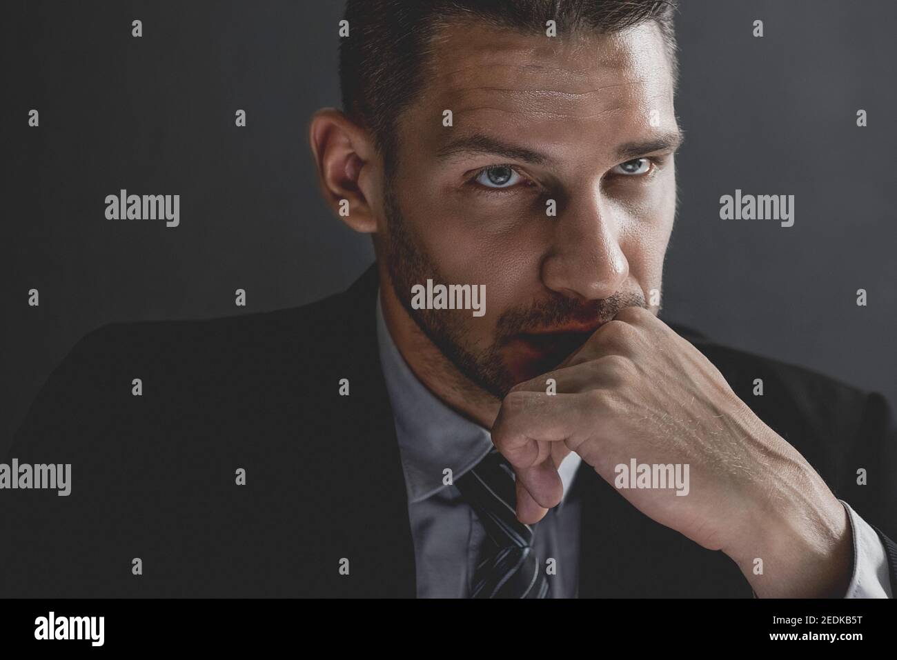 Pensive man interviewer in shadow with serious face staring at ...